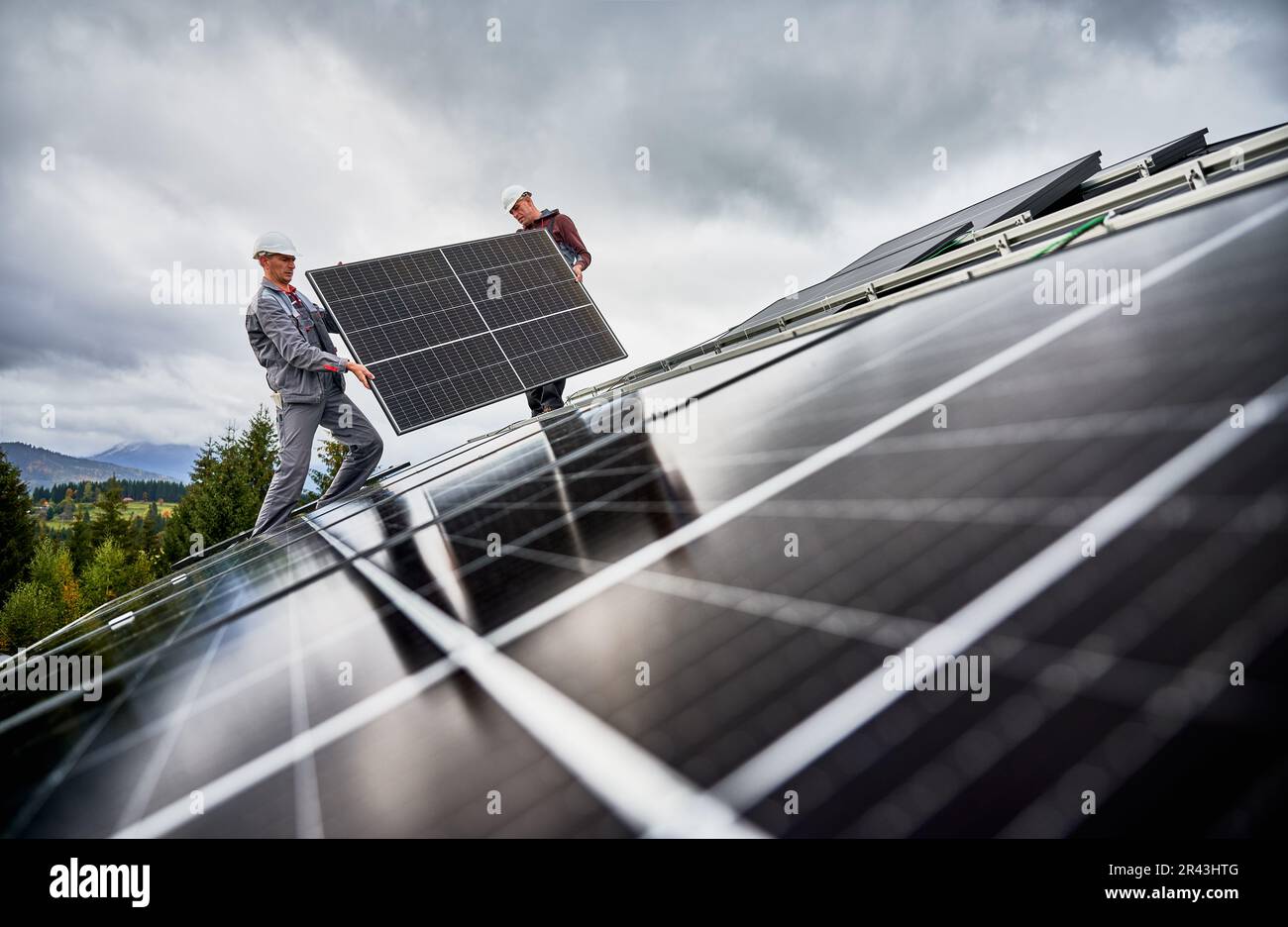 Workers building solar panel system on roof of house. Men technicians ...