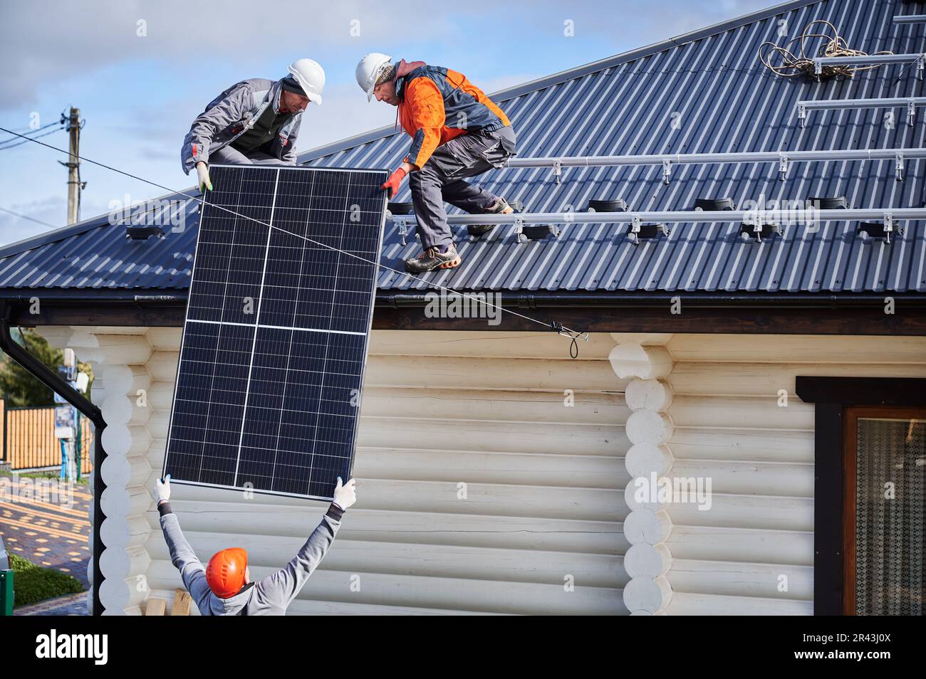Men builders installing solar panel system on roof of house ...