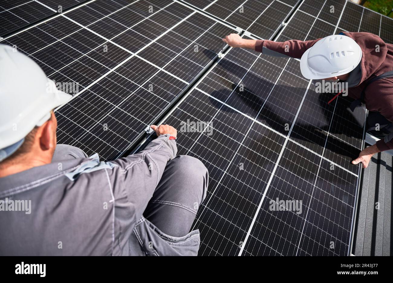 Technicians installing photovoltaic solar panels on roof of house. Men ...