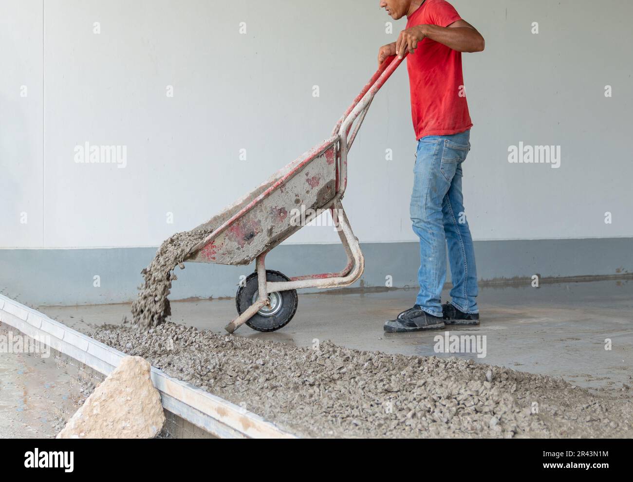 Workers push cement trucks to pour the floor inside to prepare for ...