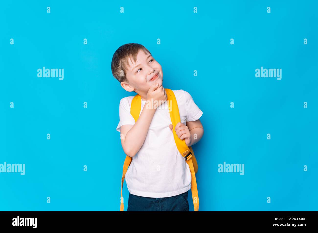 Boy with a yellow backpack thought in front of a blue background Stock ...