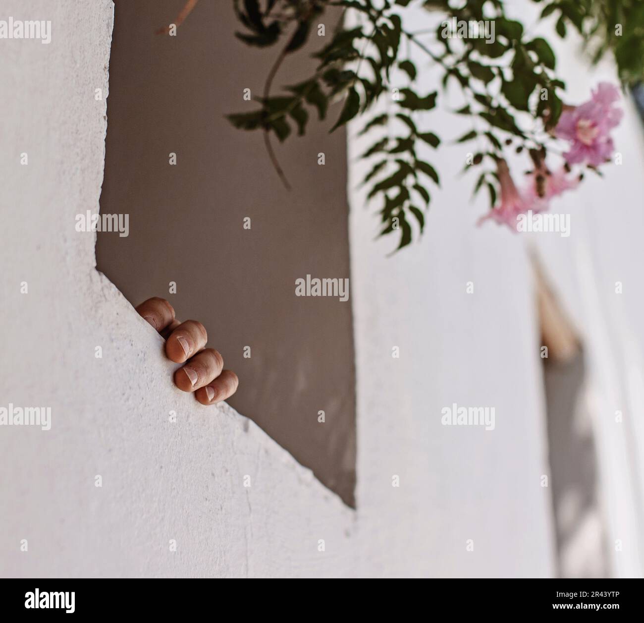 A hand holds on to a window sill of a stucco building in Marrakesh ...