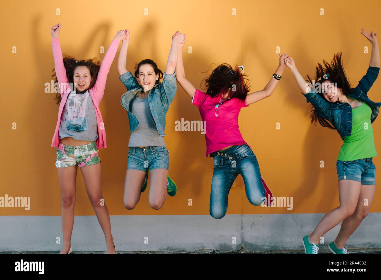 happy girls hold hands and jump Stock Photo - Alamy