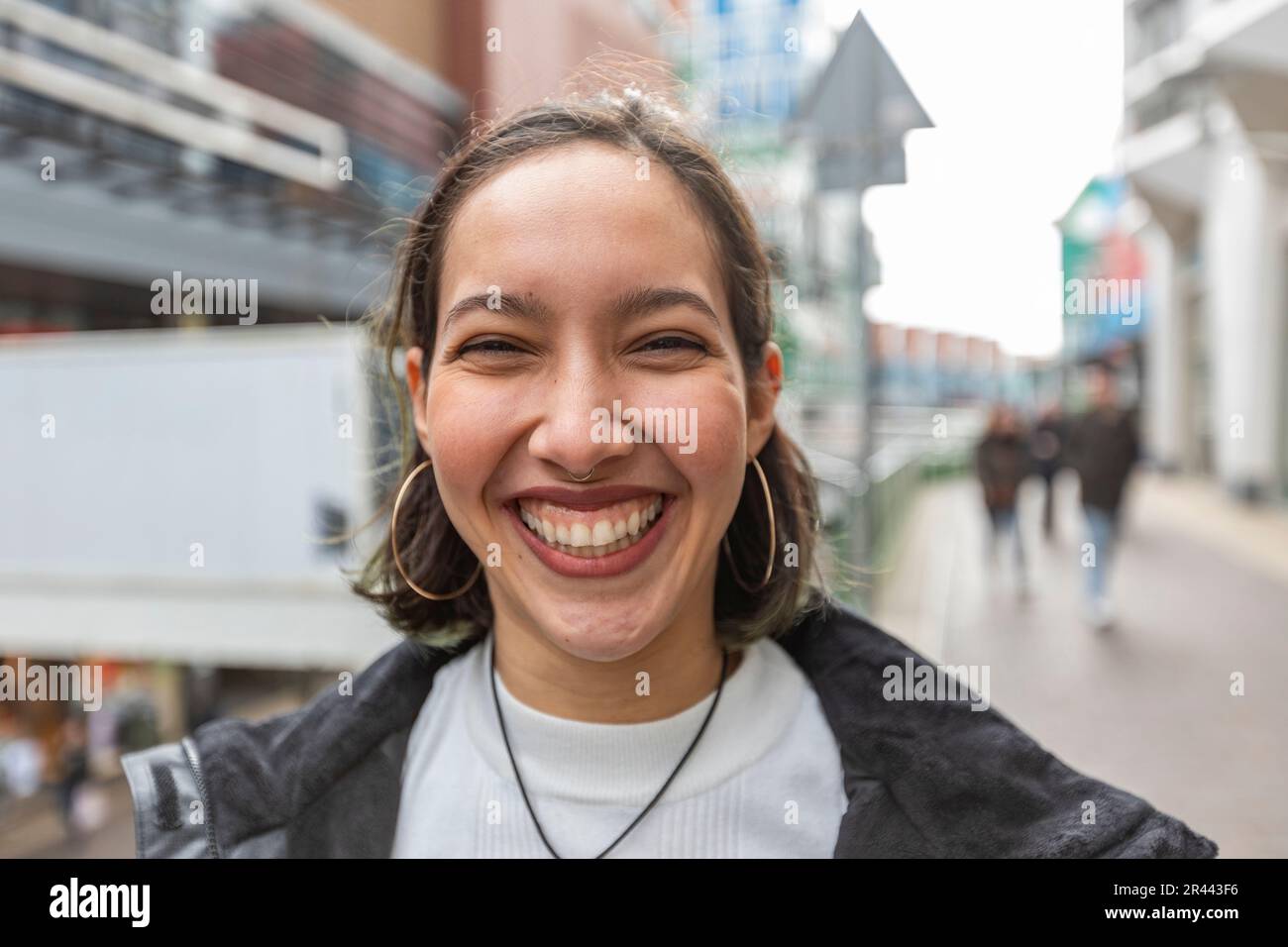 Mixed race woman with wide smile standing on street in city Stock Photo ...