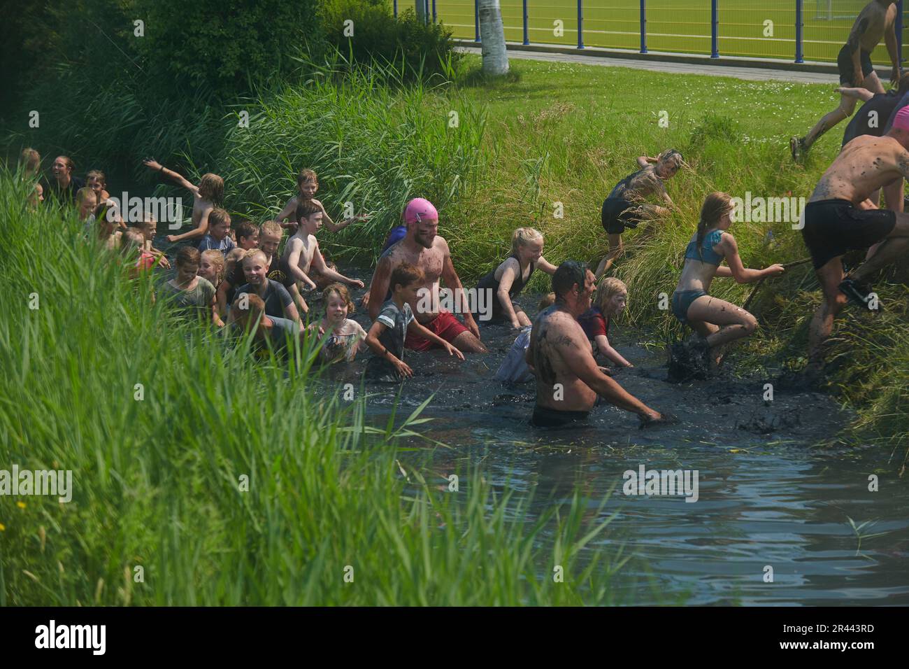 Group of people in a muddy ditch having fun during survival weekend ...