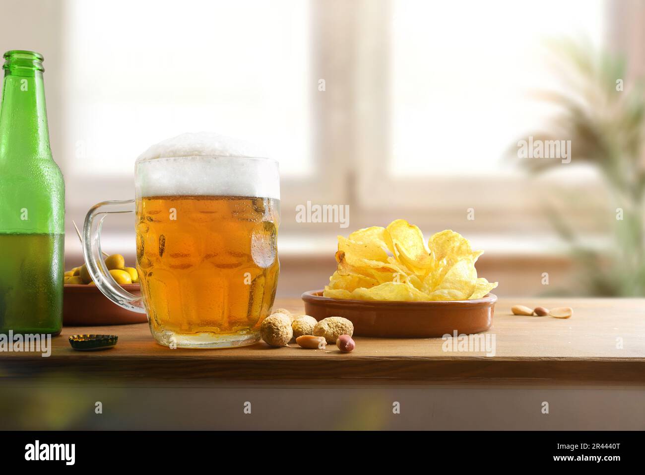 Snack on wooden bench with beer mug, chips and peanuts in a room with a ...