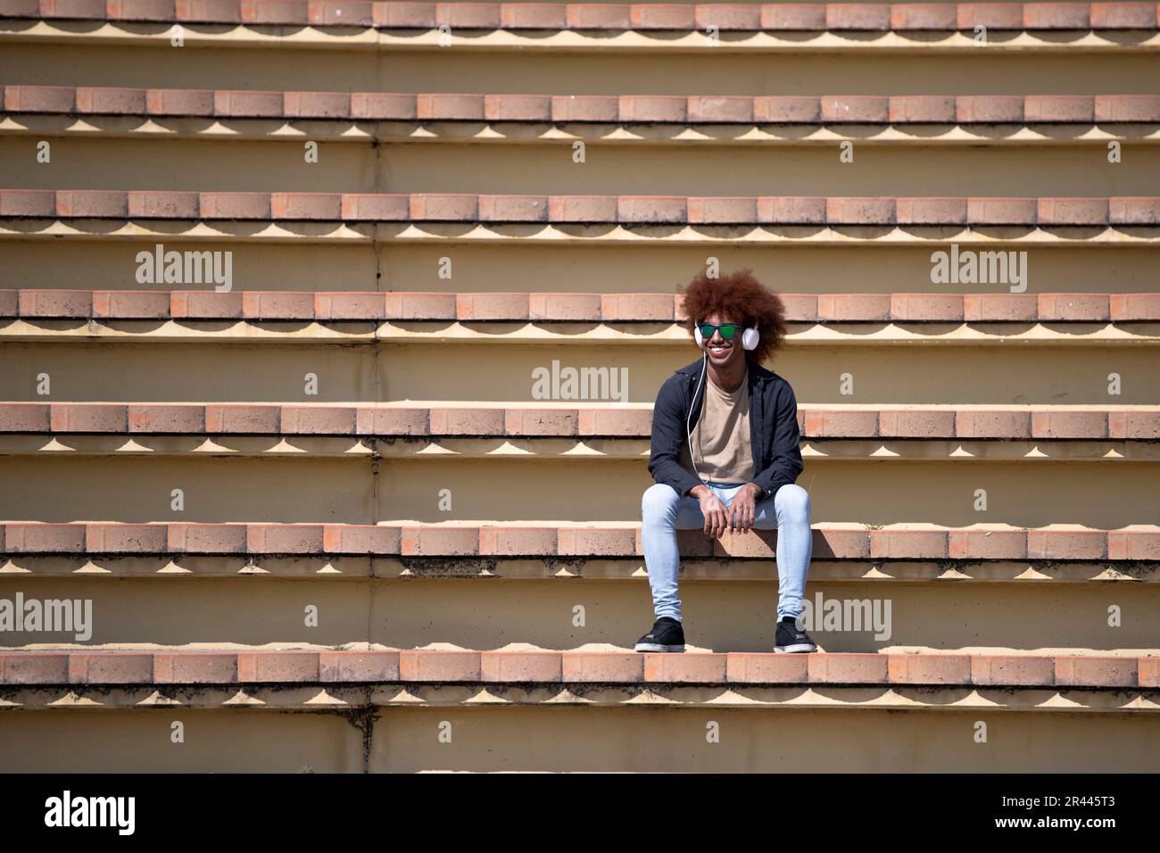 Cheerful happy young man sitting alone on a concrete bleacher Stock ...