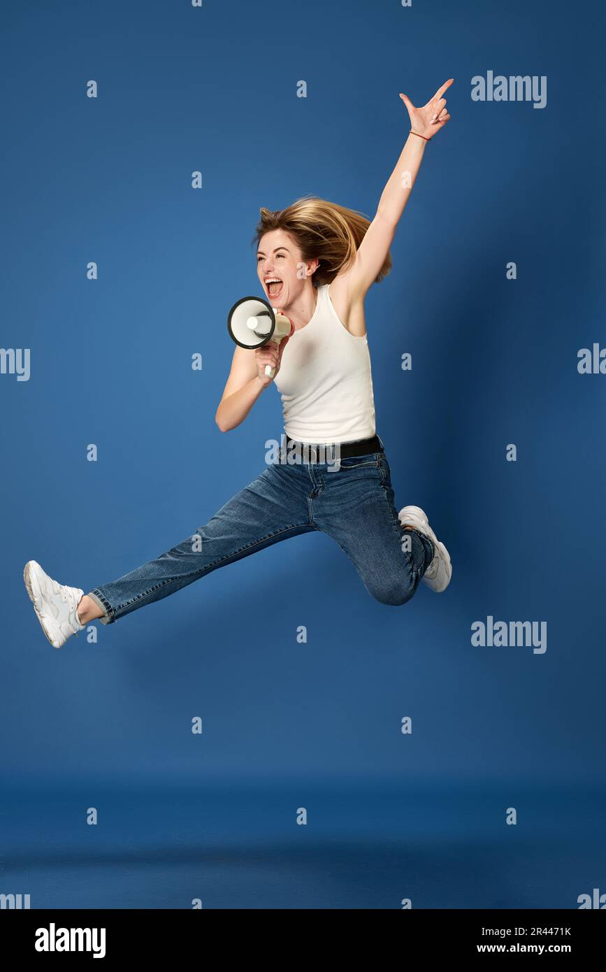 Full-length portrait of young woman in casual clothes posing, jumping ...