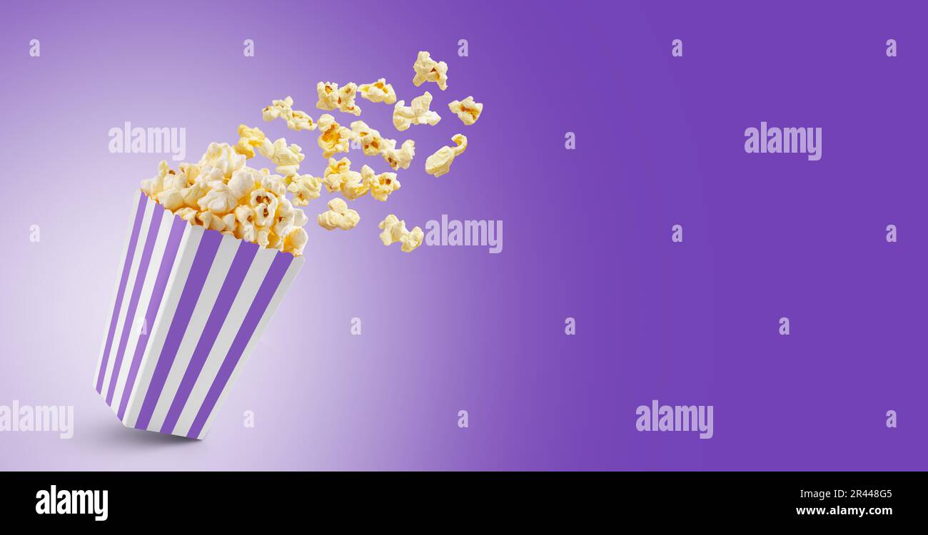 Popcorn flying out of purple white striped paper box isolated on purple ...
