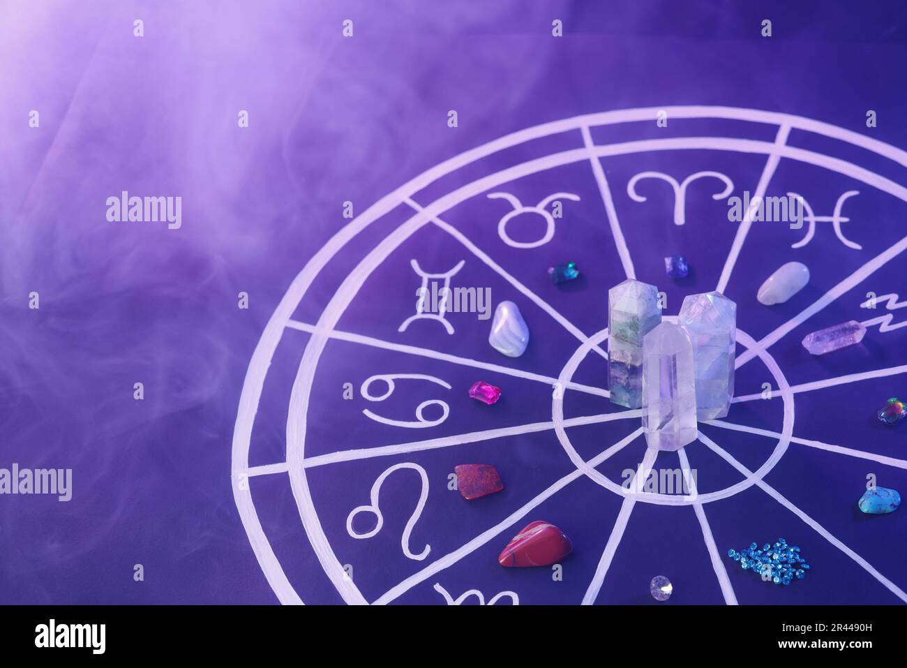 Natural stones for zodiac signs and drawn astrology chart on dark blue ...