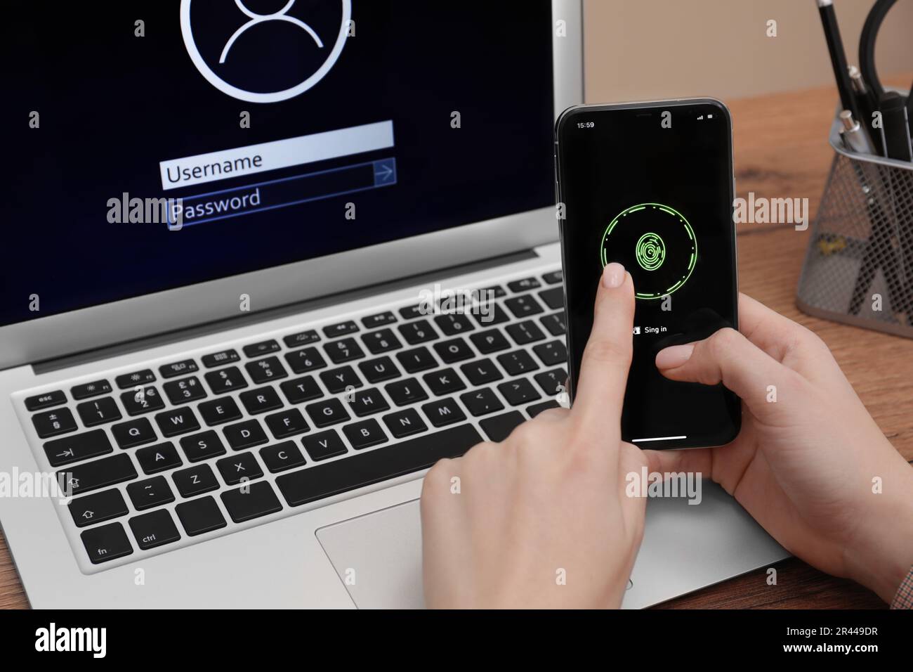 Woman unlocking smartphone with fingerprint identification near laptop ...