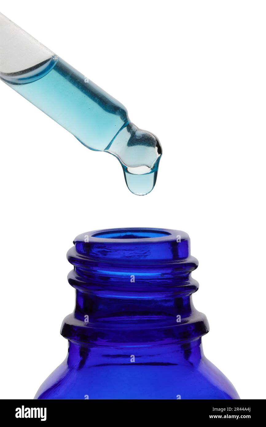 Dripping light blue facial serum from pipette into glass bottle on ...