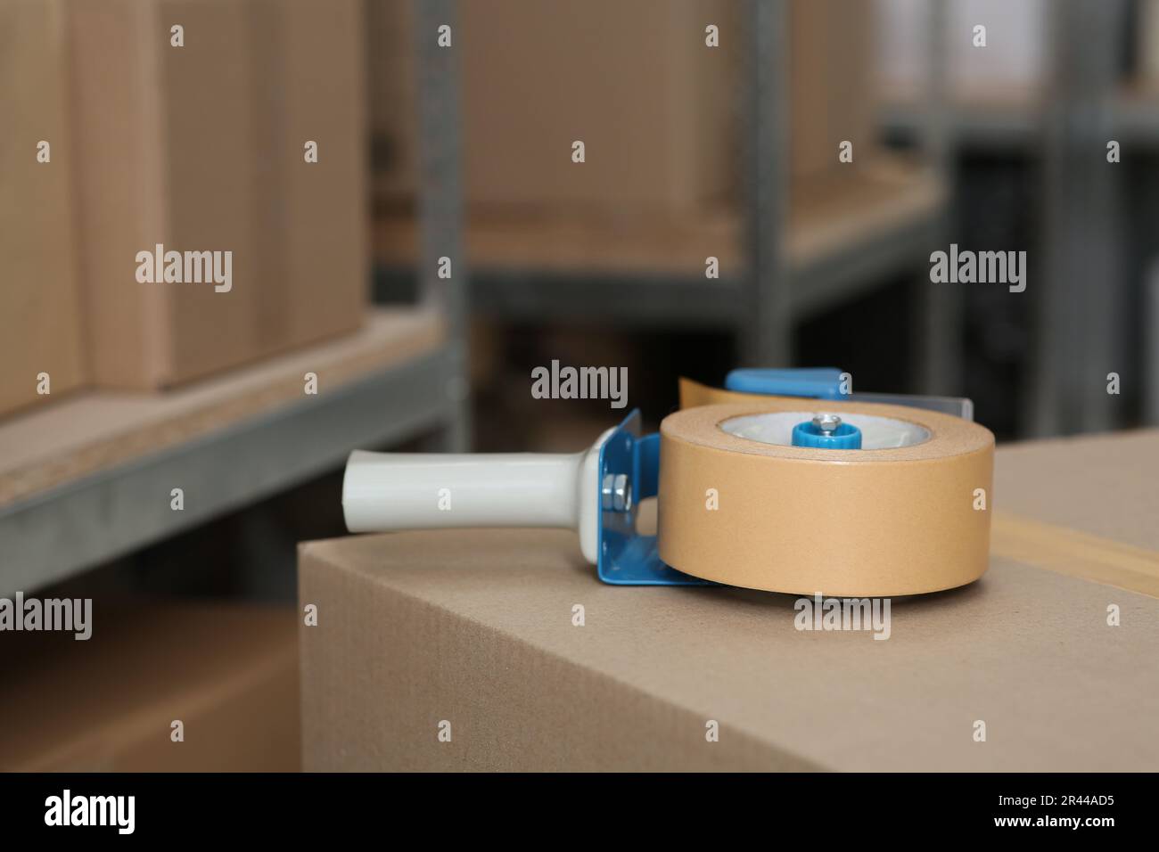 Adhesive tape dispenser on cardboard box indoors Stock Photo - Alamy