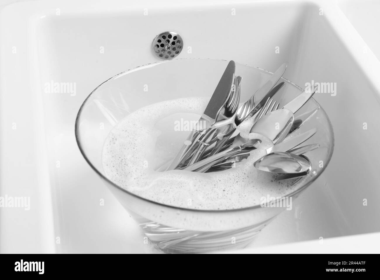 Washing silver spoons, forks and knives in kitchen sink Stock Photo - Alamy