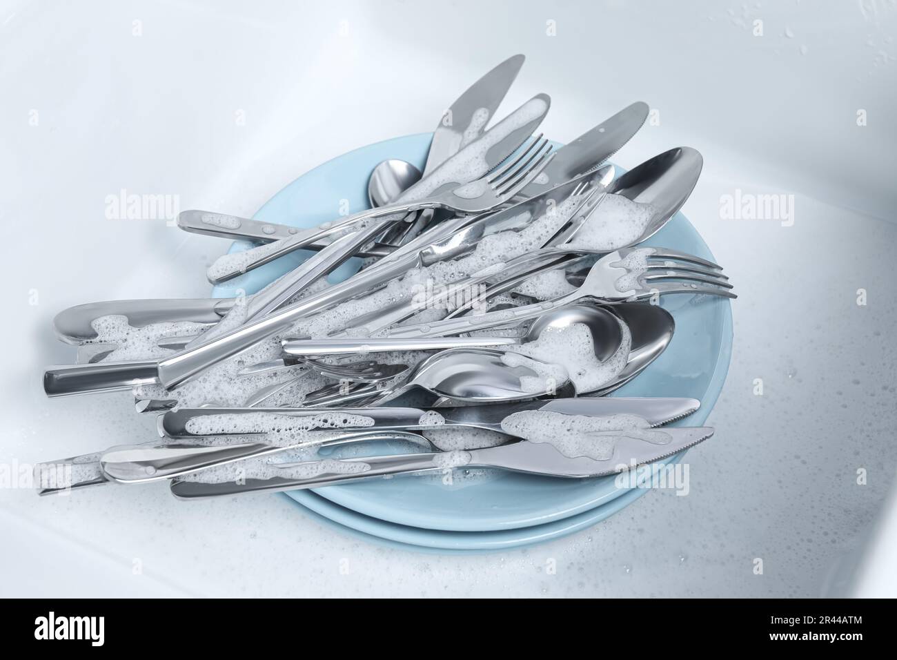 Washing silver spoons, forks and knives in foam Stock Photo - Alamy