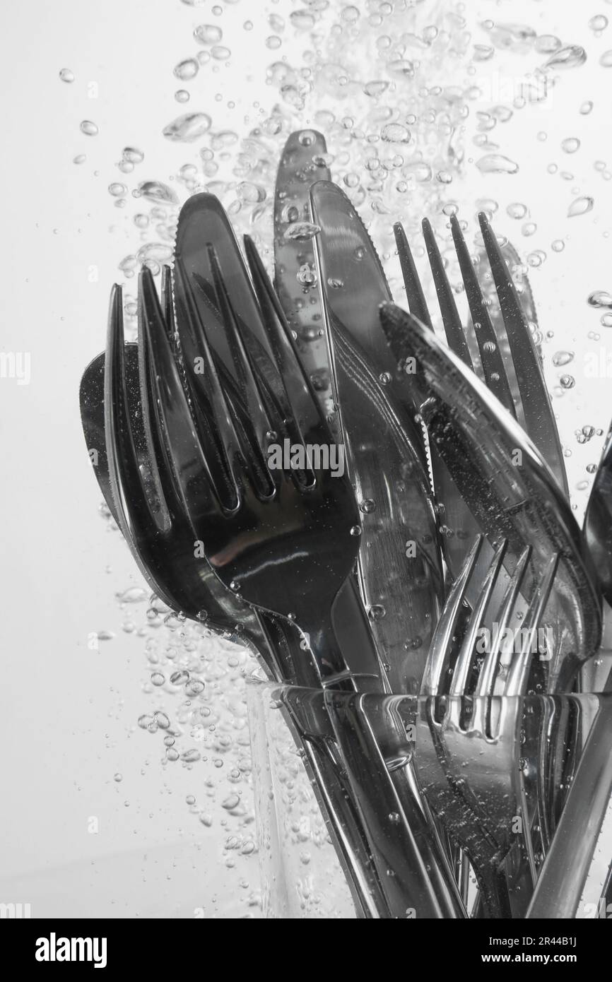 Washing silver cutlery in water on white background Stock Photo - Alamy
