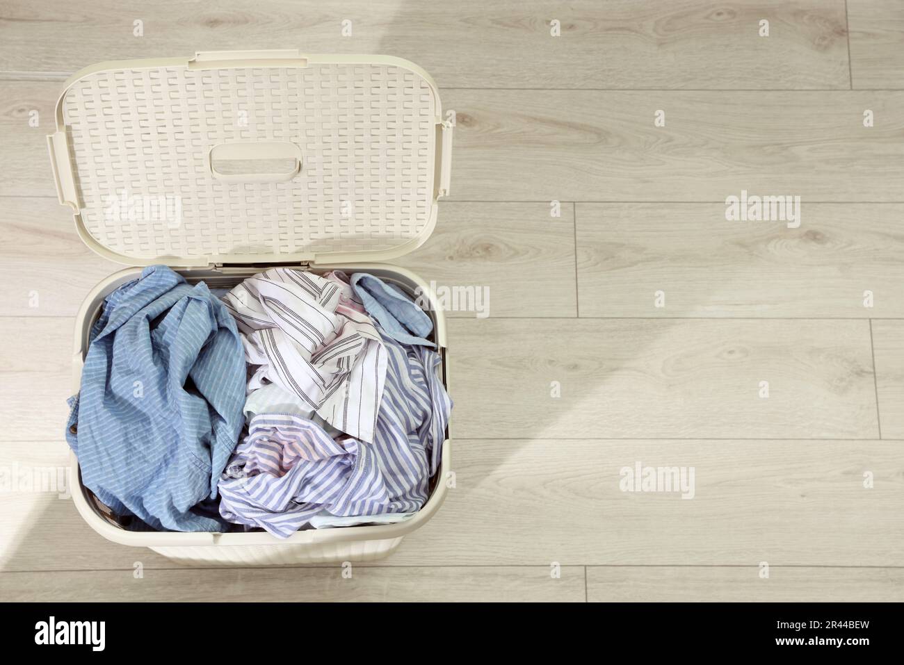 Laundry basket with clothes on floor, top view. Space for text Stock ...