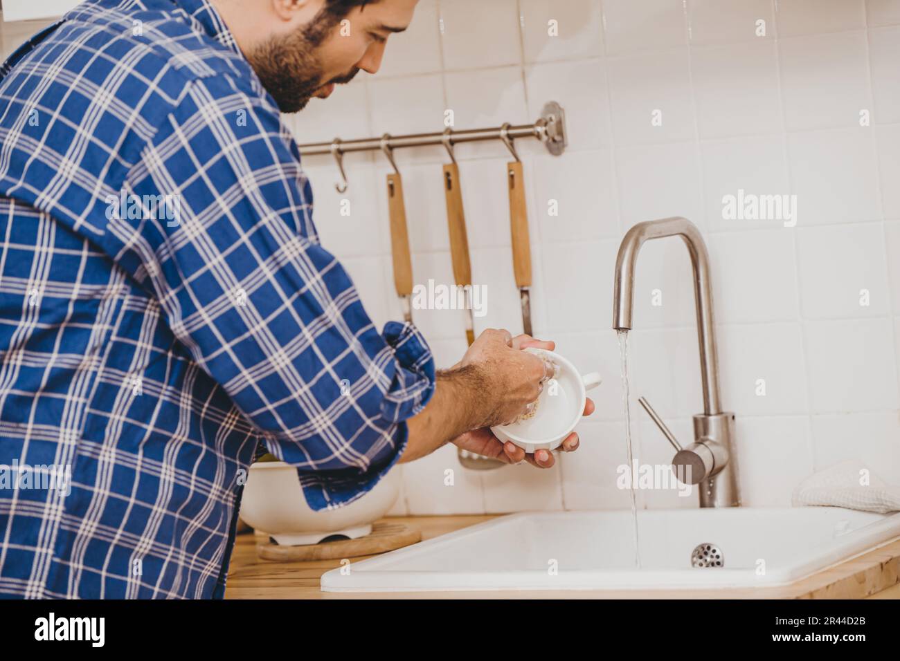 Man doing chores cleaning dishes cup at home kitchen sink holiday ...