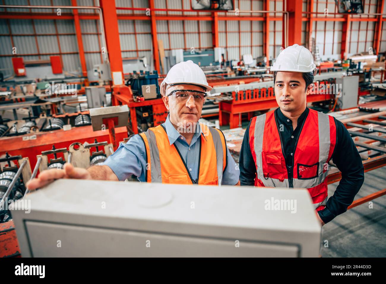Young engineer standing with senior supervisor teamwork in metal ...