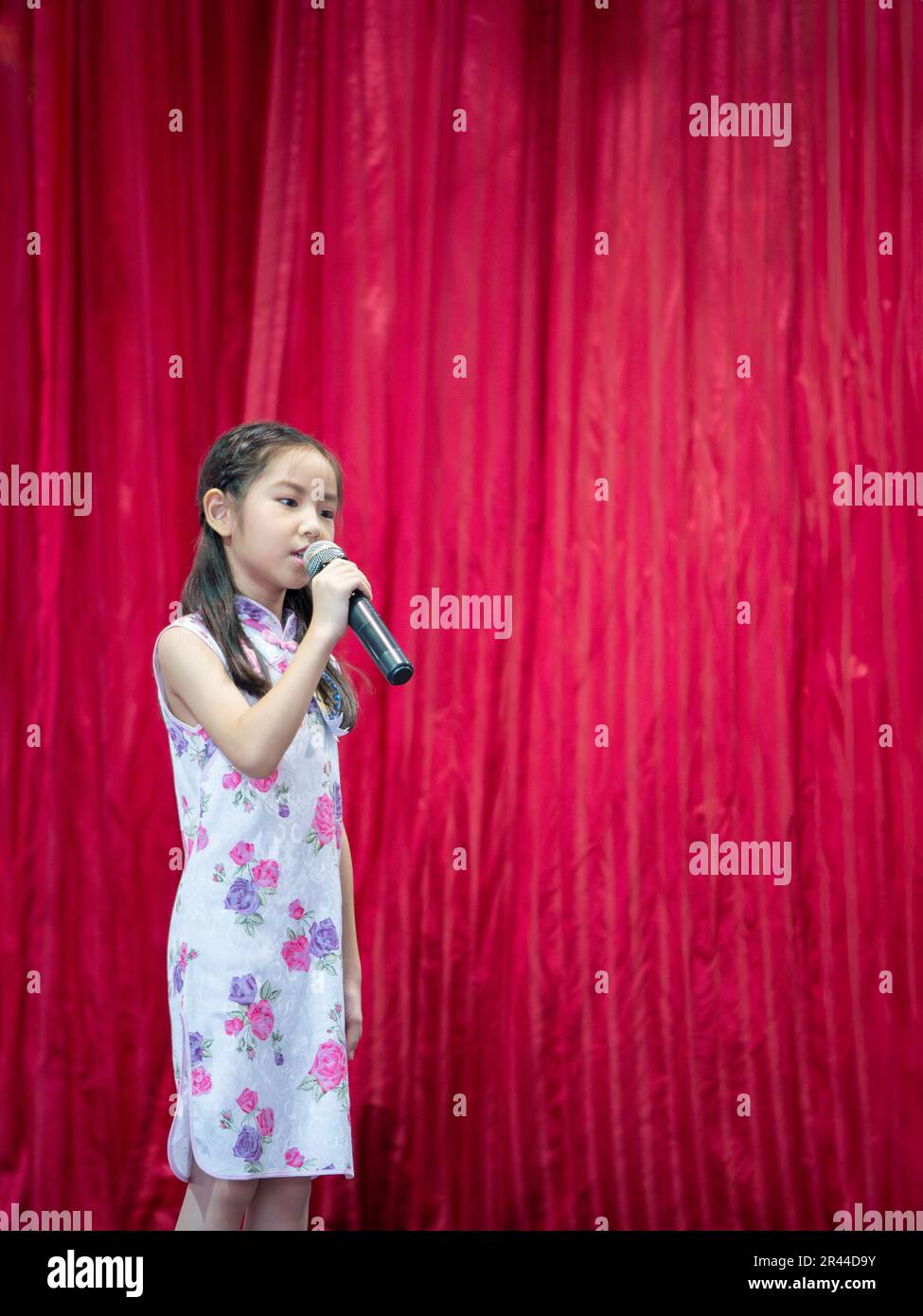 The Asian kid girl sing a song on stage at her school activity day ...