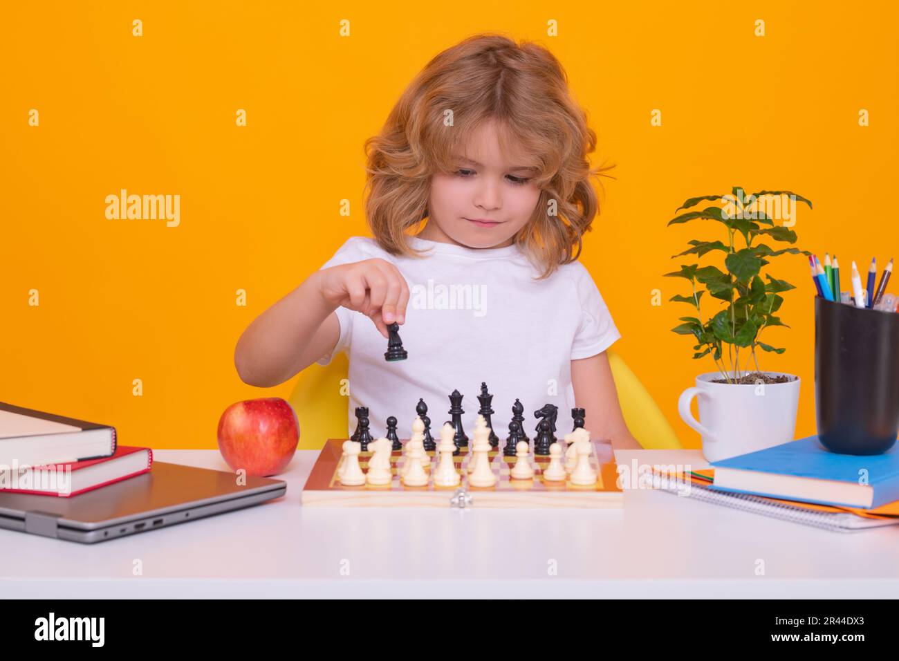 Child with chess on yellow isolated studio background. Child think about chess game. Intelligent ...