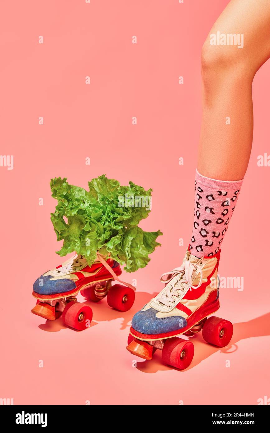 Female leg in vintage rollers and funny socks with lettuce against pink ...