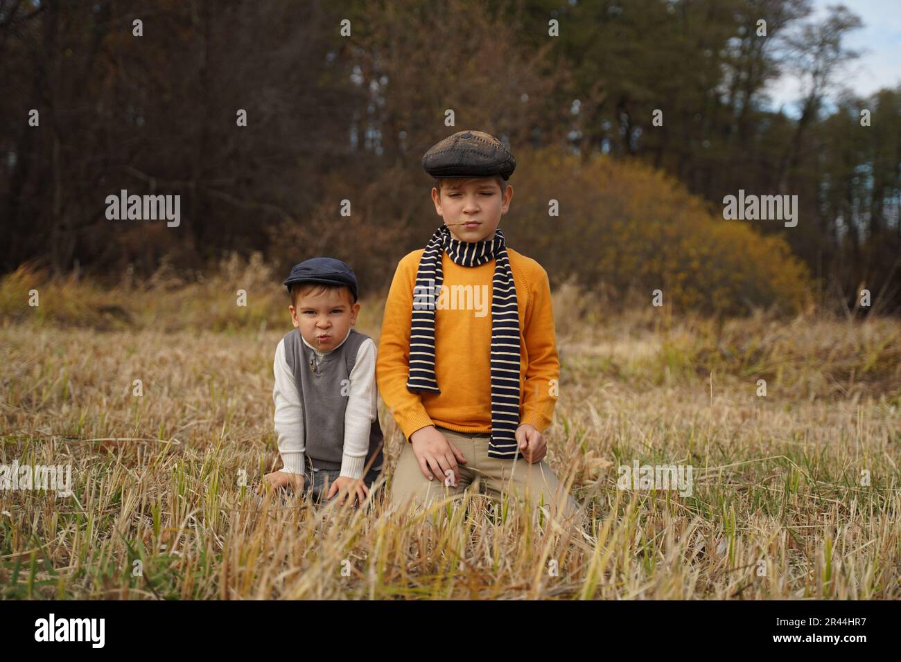 Children sit in nature and hold blades of grass in their mouths. The ...