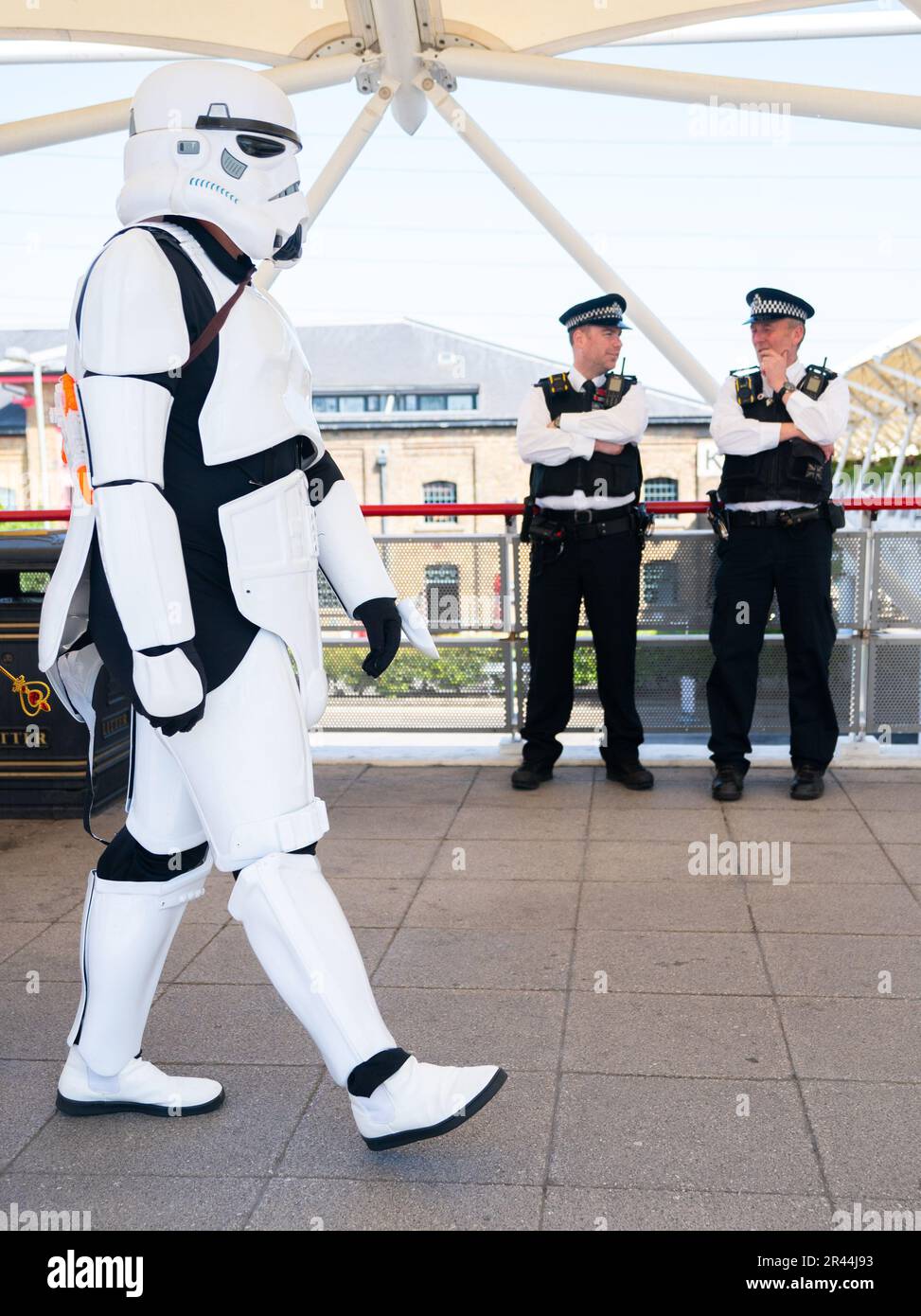 A Star Wars Storm Trooper walks past police officers during MCM Comic ...