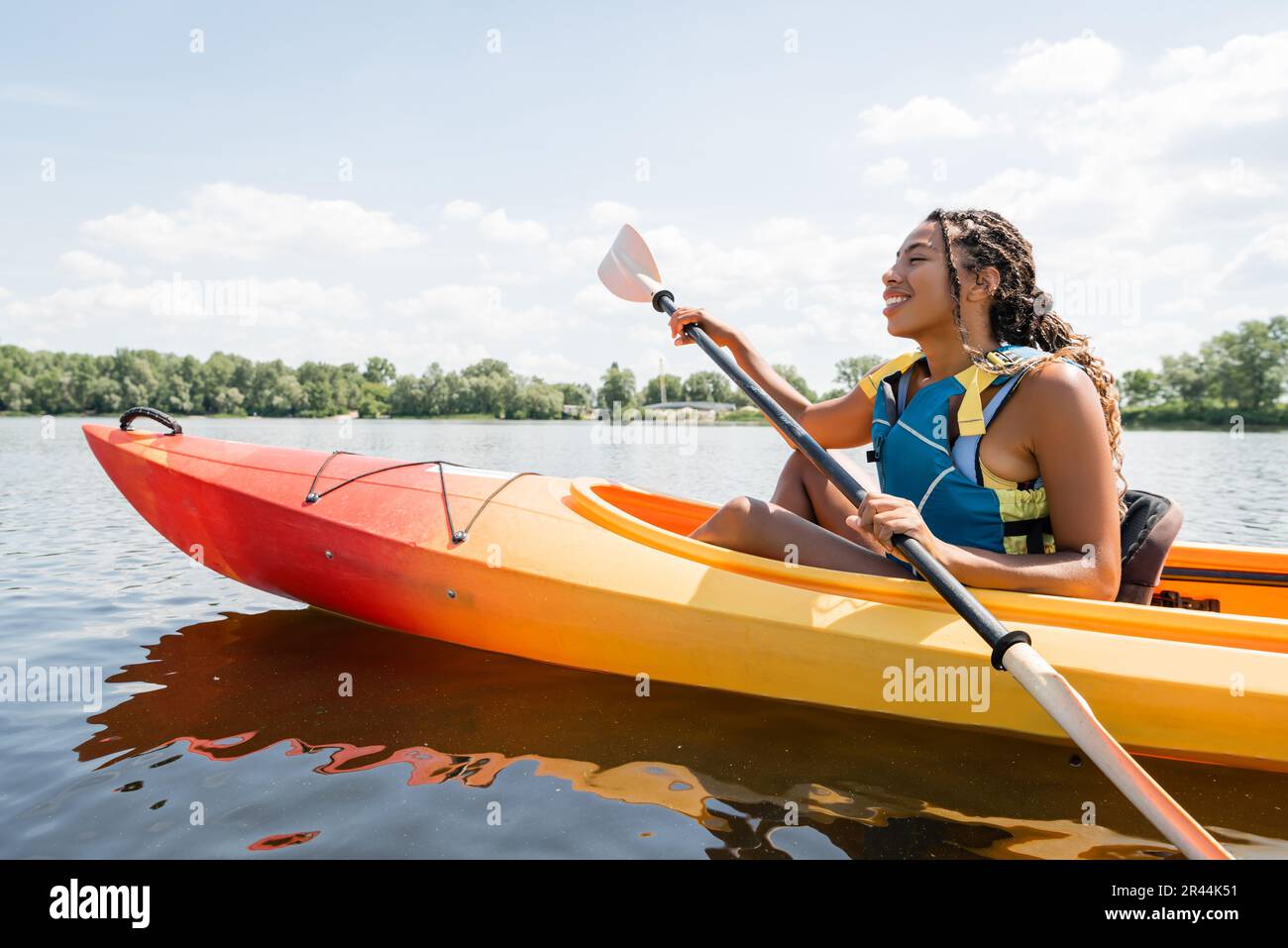 side view of carefree and active african american woman in life vest ...