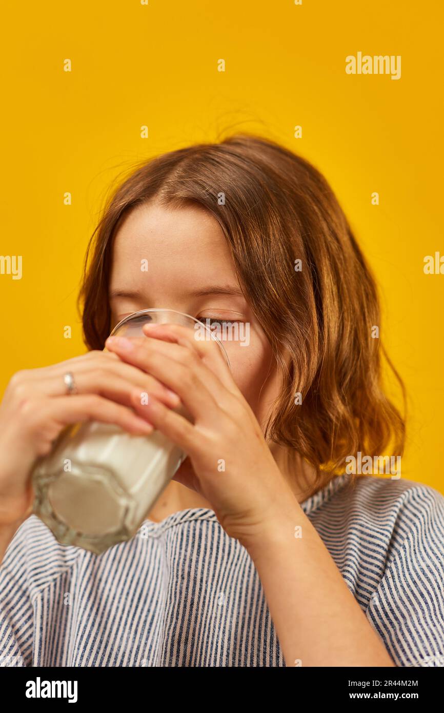 Pretty teen girl, child with a fresh glass of milk isolated on studio ...