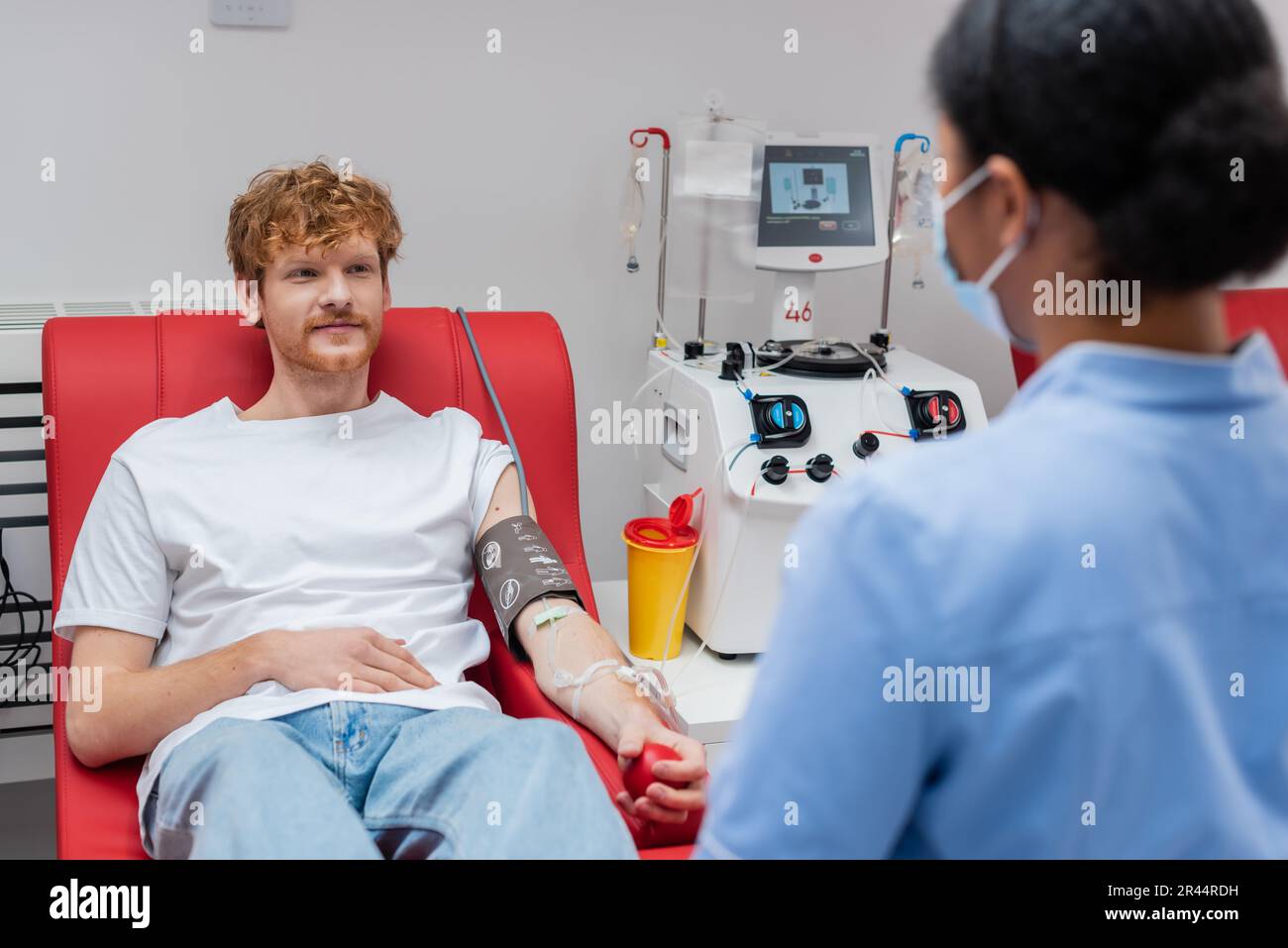 redhead man in blood pressure cuff holding rubber ball while sitting on ...