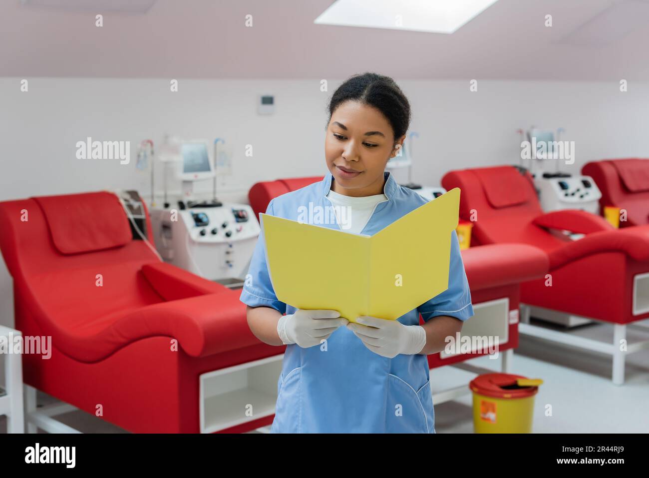 multiracial healthcare worker in blue uniform and latex gloves reading ...