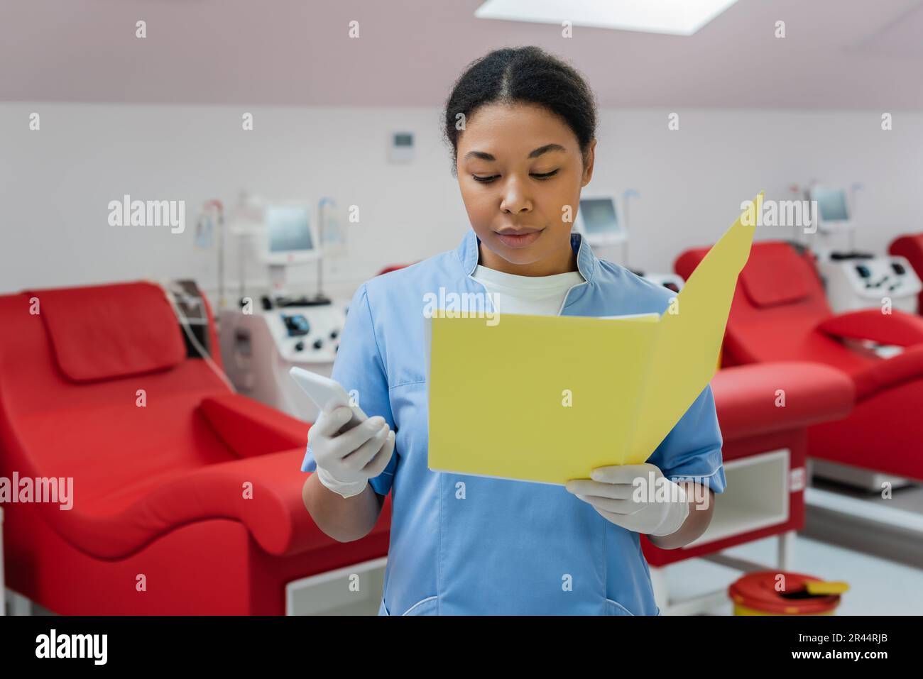 multiracial healthcare worker in blue uniform and latex gloves holding ...