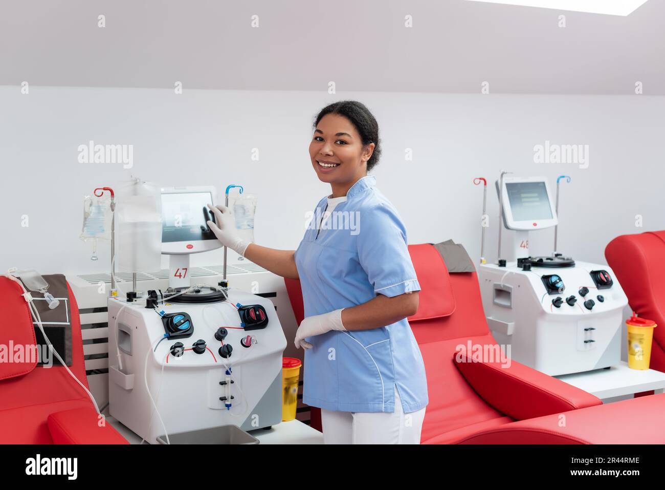 young multiracial nurse in uniform and latex gloves operating ...