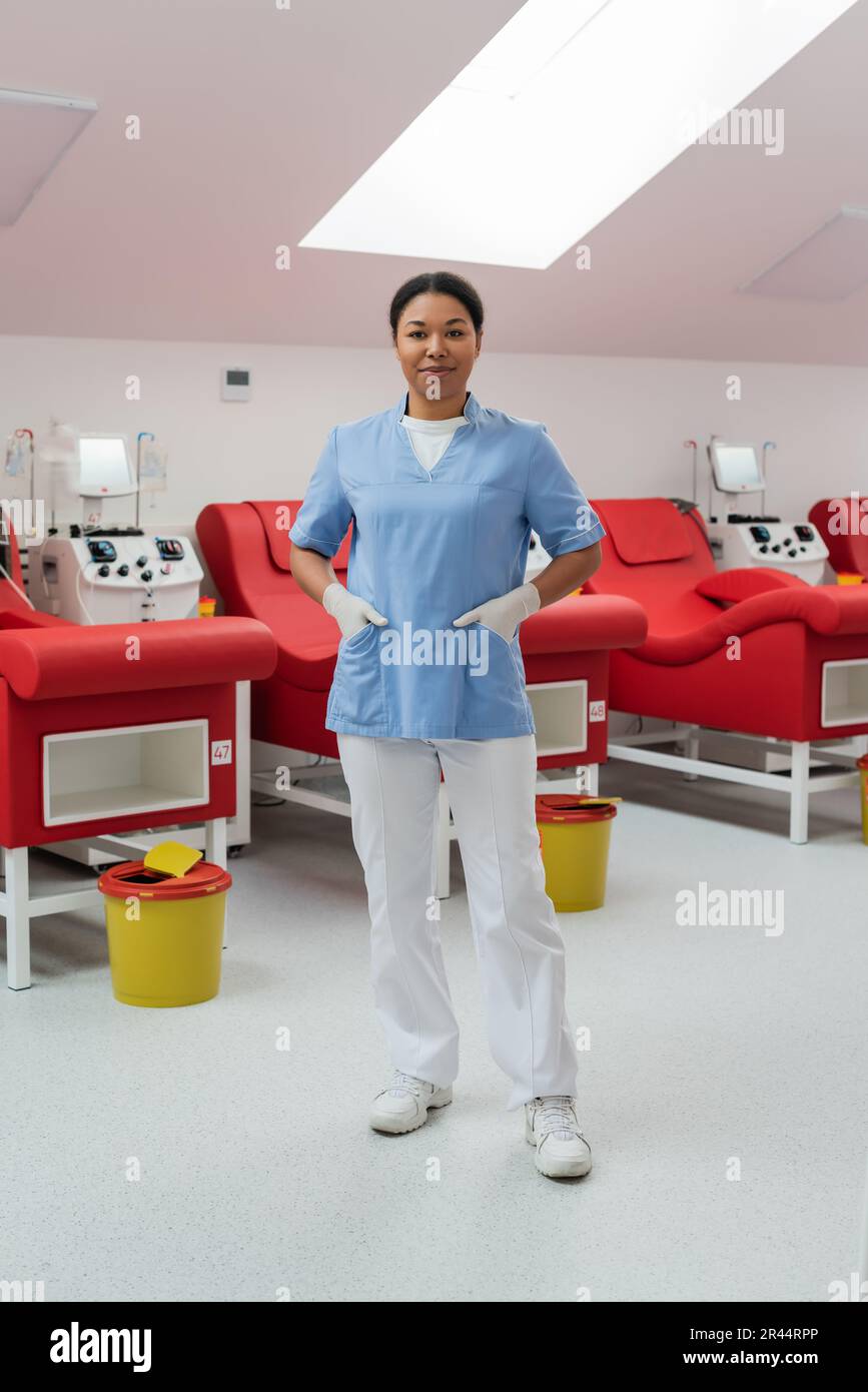 positive multiracial nurse in latex gloves standing with hands in ...