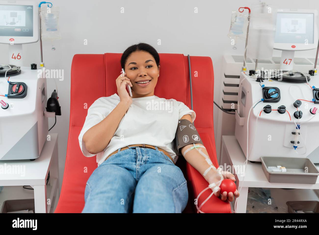 smiling multiracial woman with pressure cuff and rubber ball sitting on ...