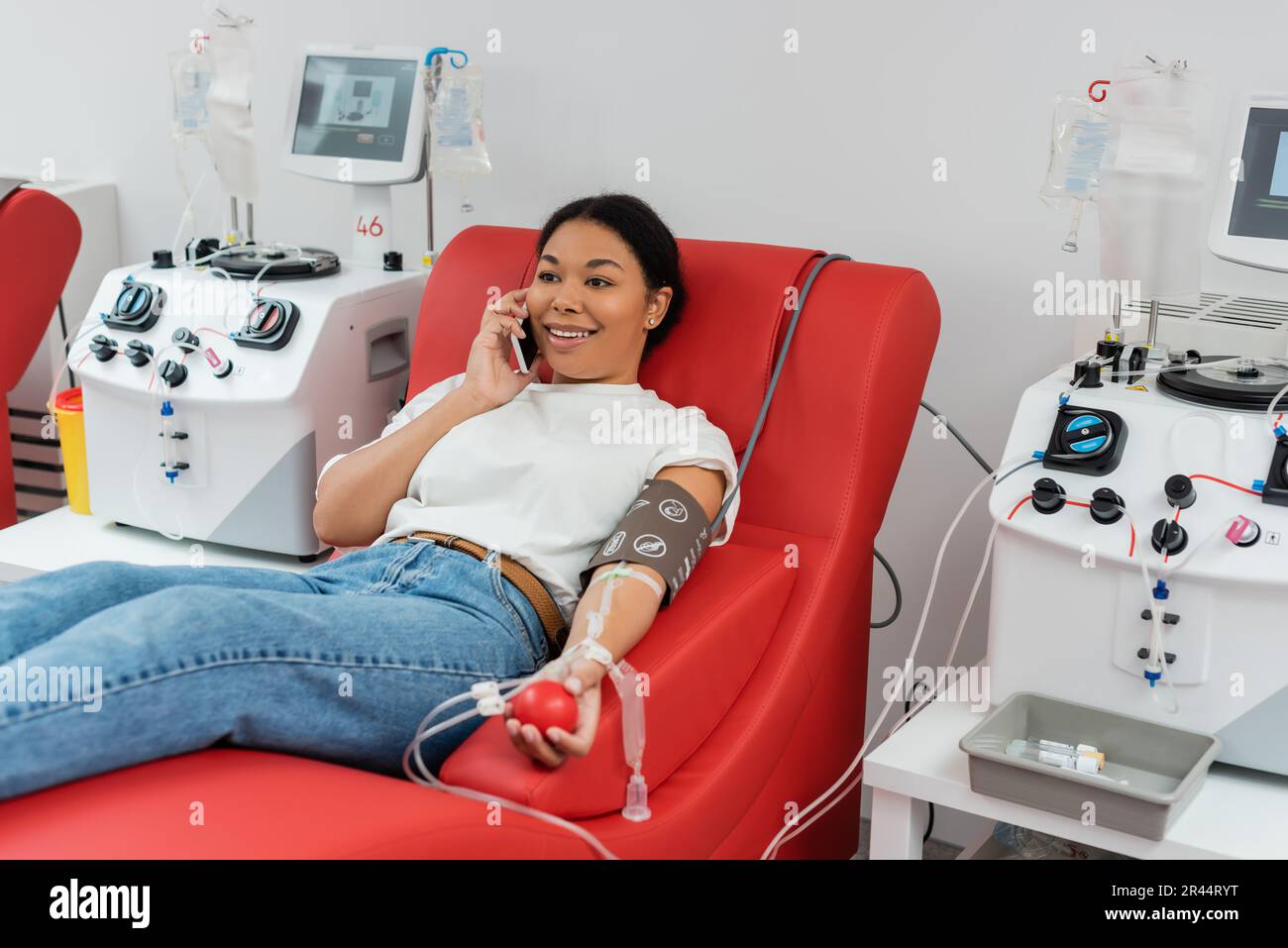 happy multiracial woman with rubber ball sitting on medical chair and ...