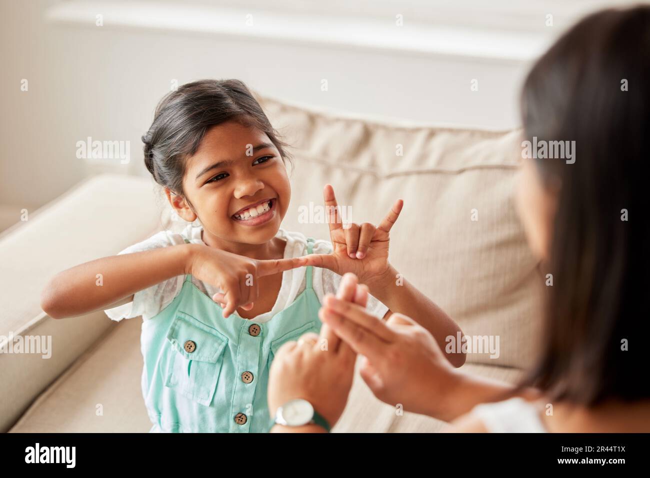 Sign language, communication and child with her mother in the living ...