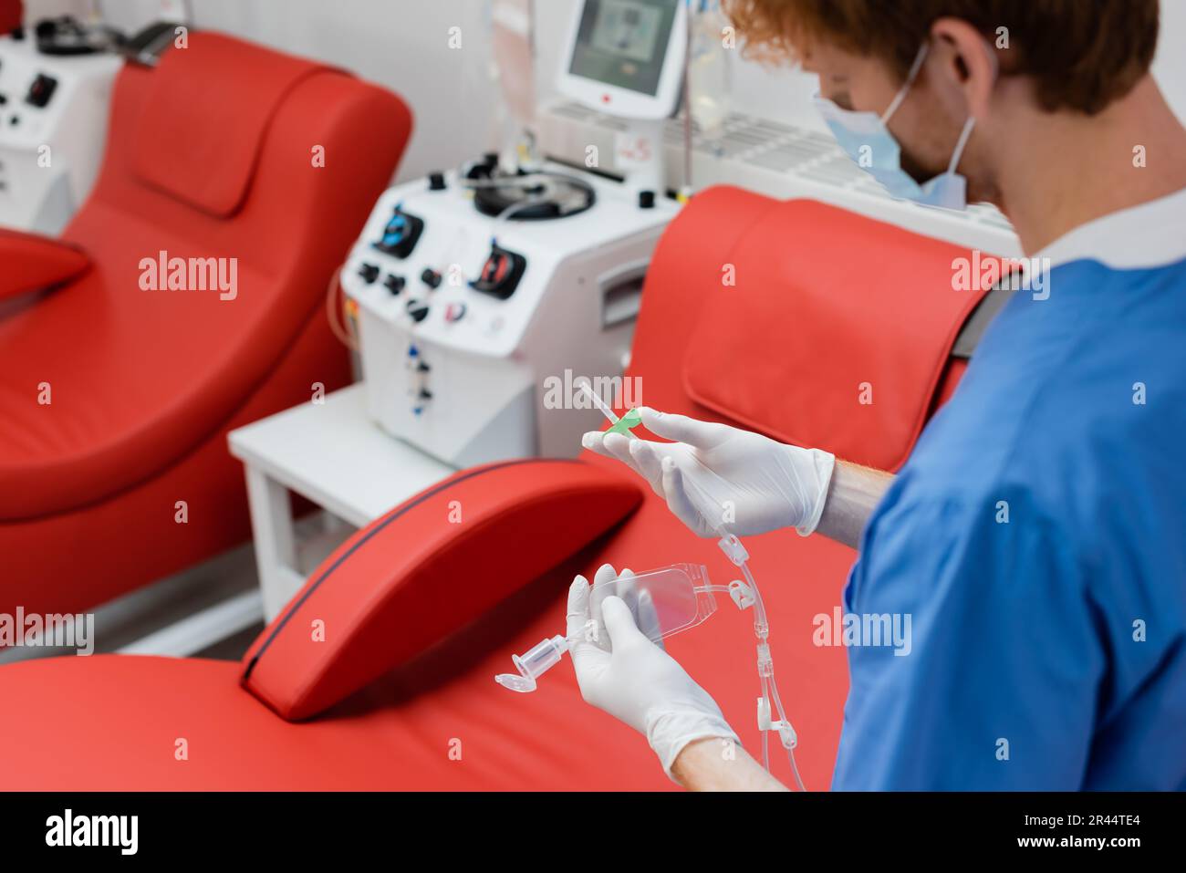 young practitioner in blue uniform and sterile latex gloves holding ...