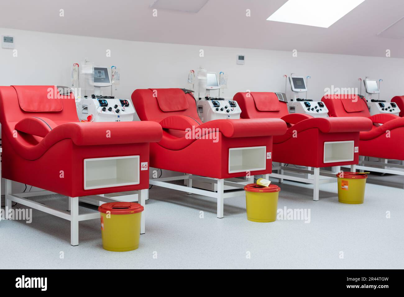 row of modern and comfortable medical chairs near transfusion machines ...