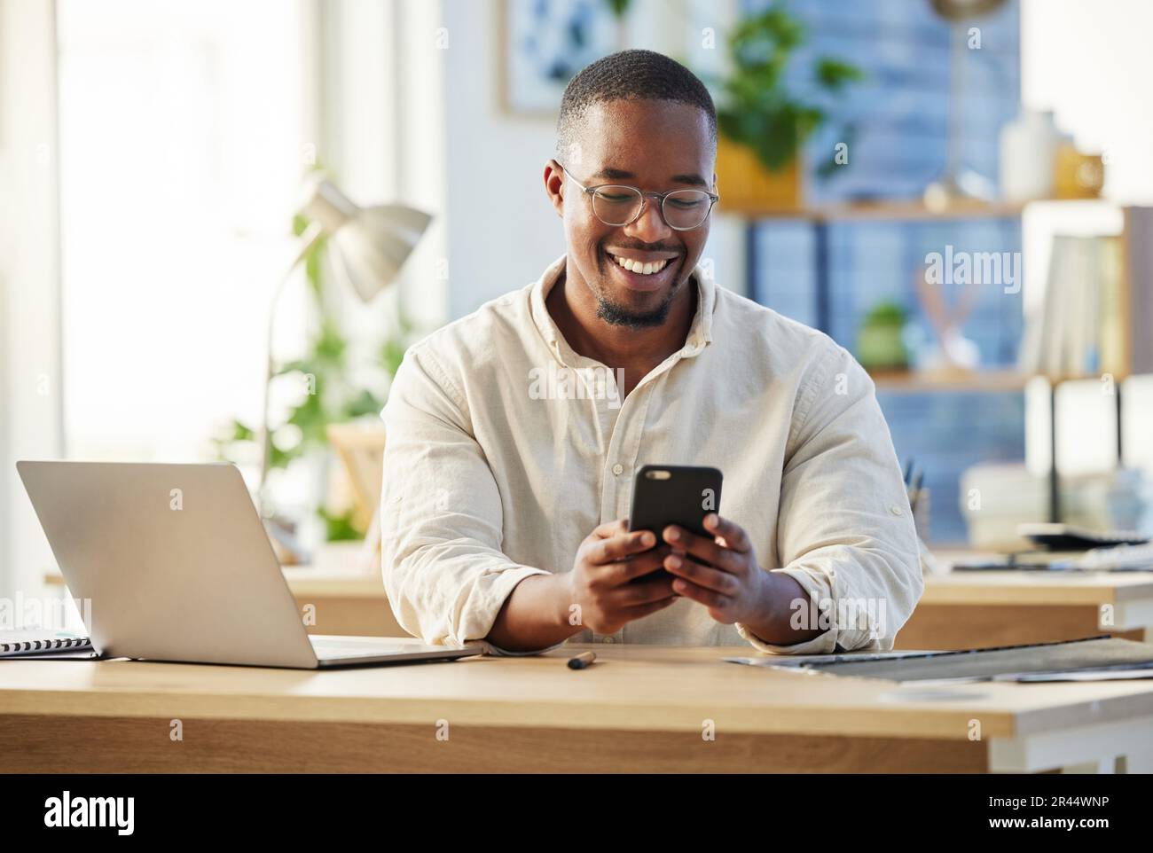 African business man, texting and phone in office with smile ...