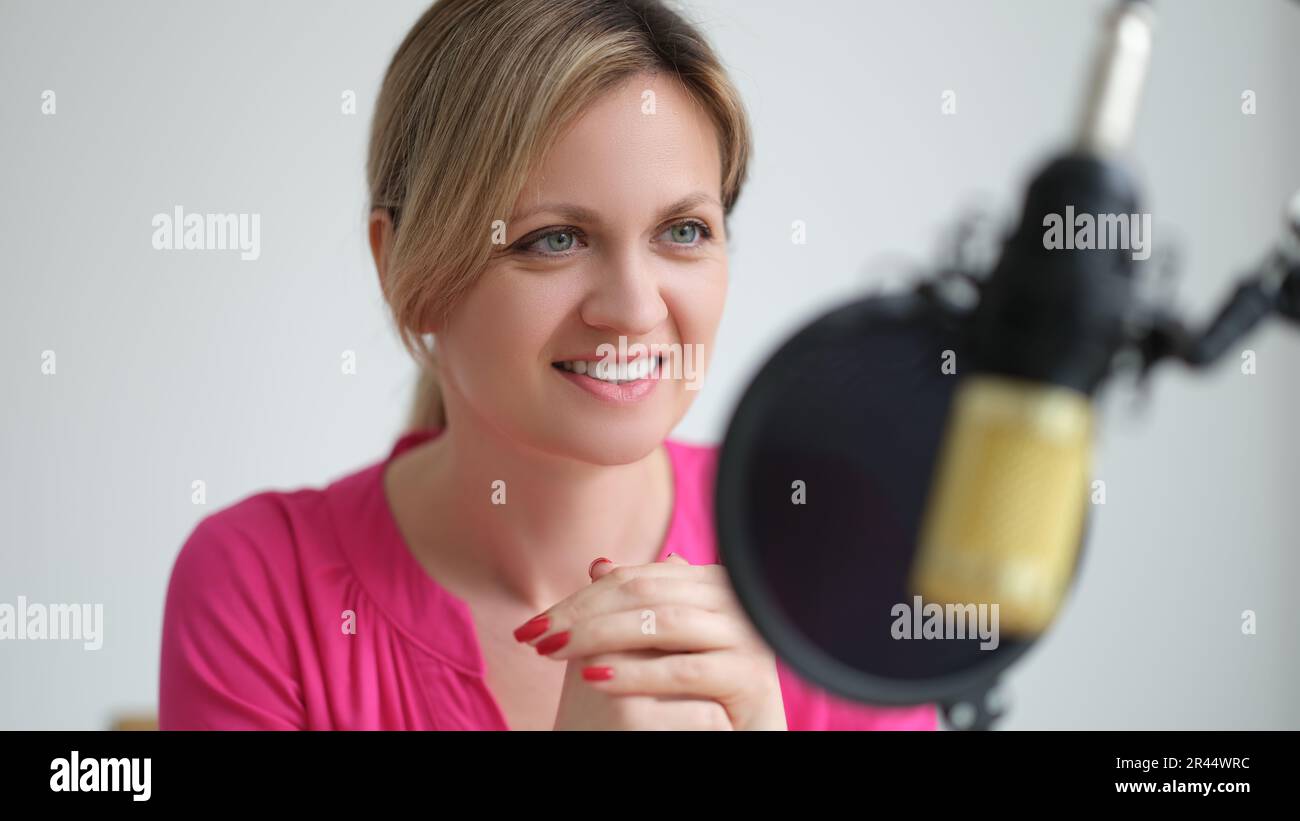 Woman radio presenter speaking into microphone in recording studio ...