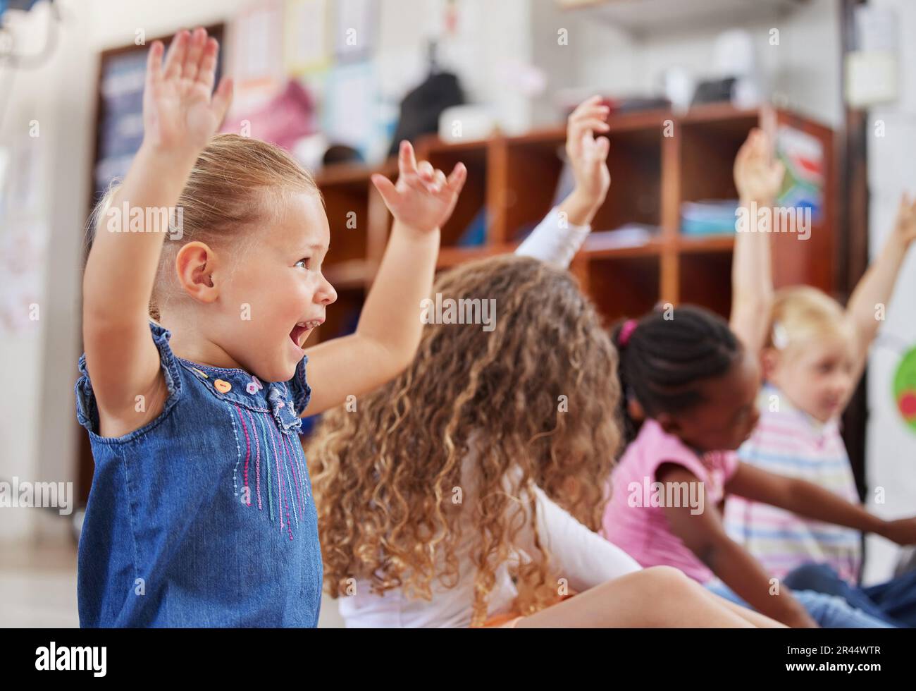 School, raise hands and children in a classroom for education or ...