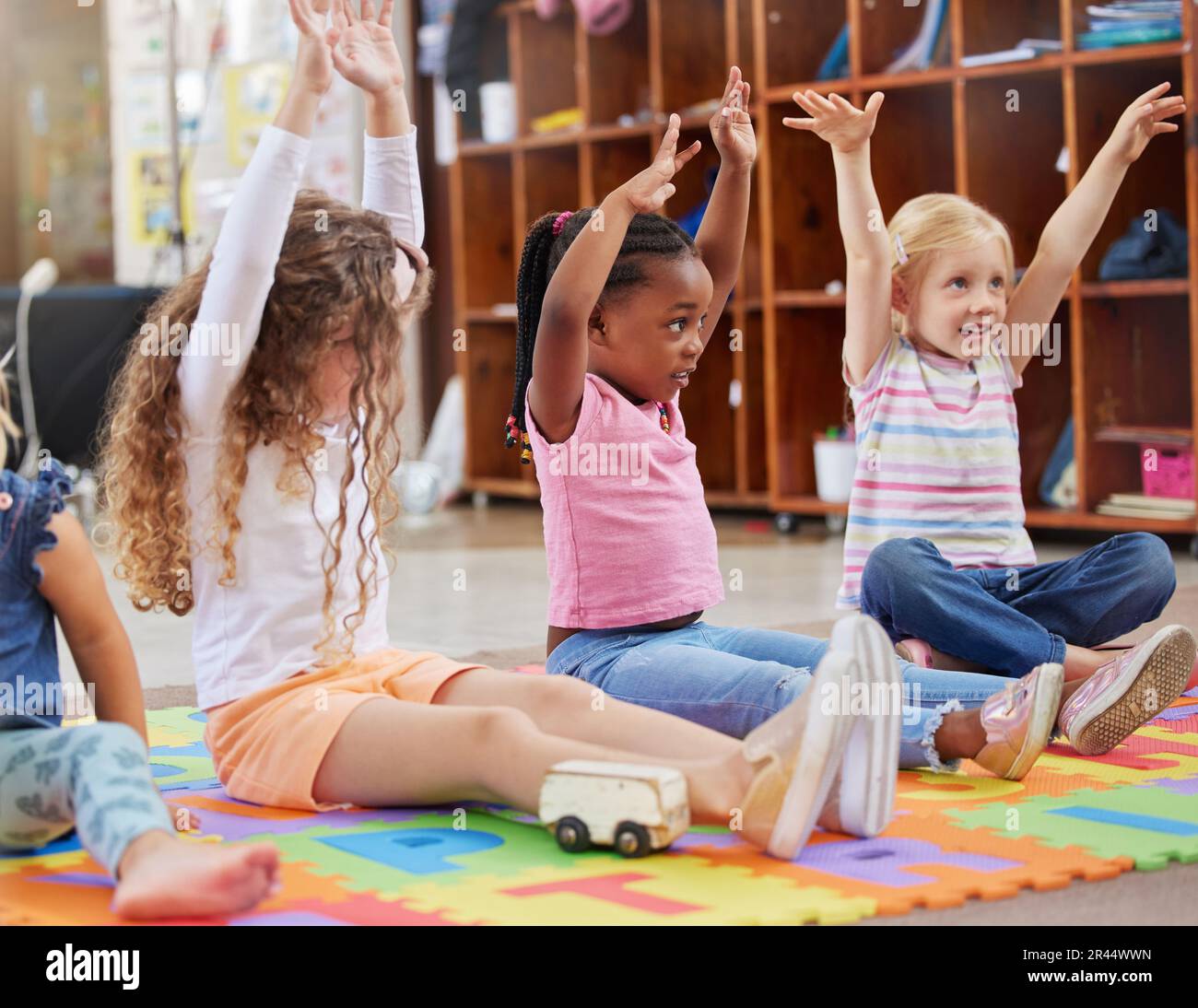 Education, raise hands and children in kindergarten in a classroom for ...