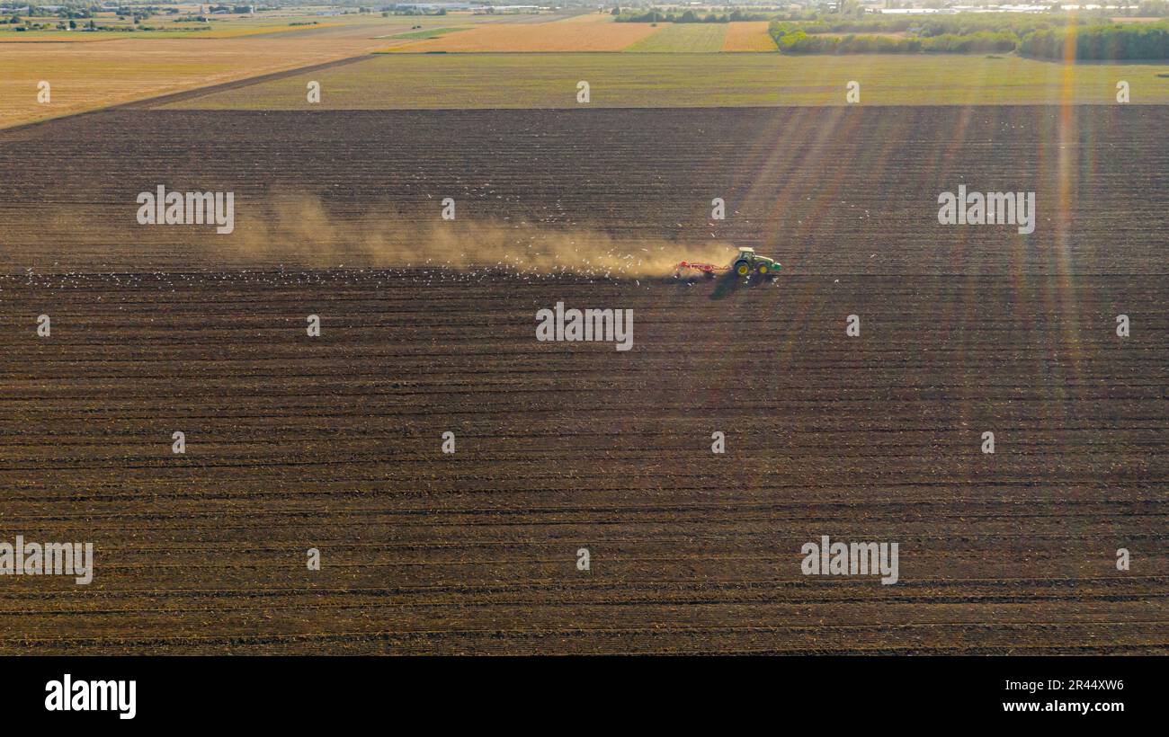 Above view with backlight, tractor pull disc harrow, harrowing farmland ...
