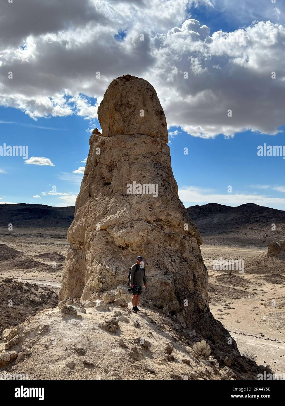 A vertical of a man stands in the desert landscape of Trona Pinnacles ...