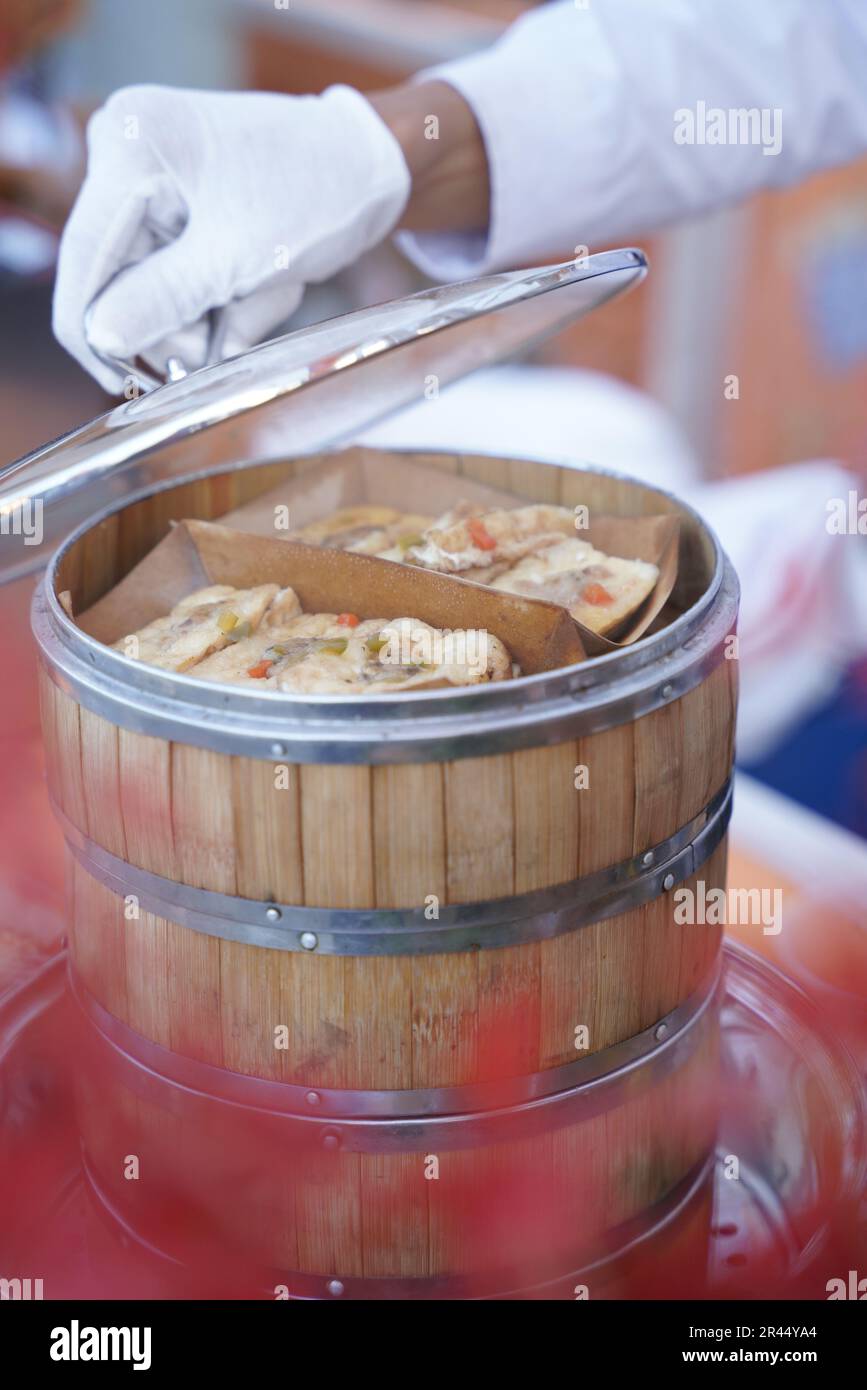 An person dishing out food from a wooden barrel at a buffet-style ...