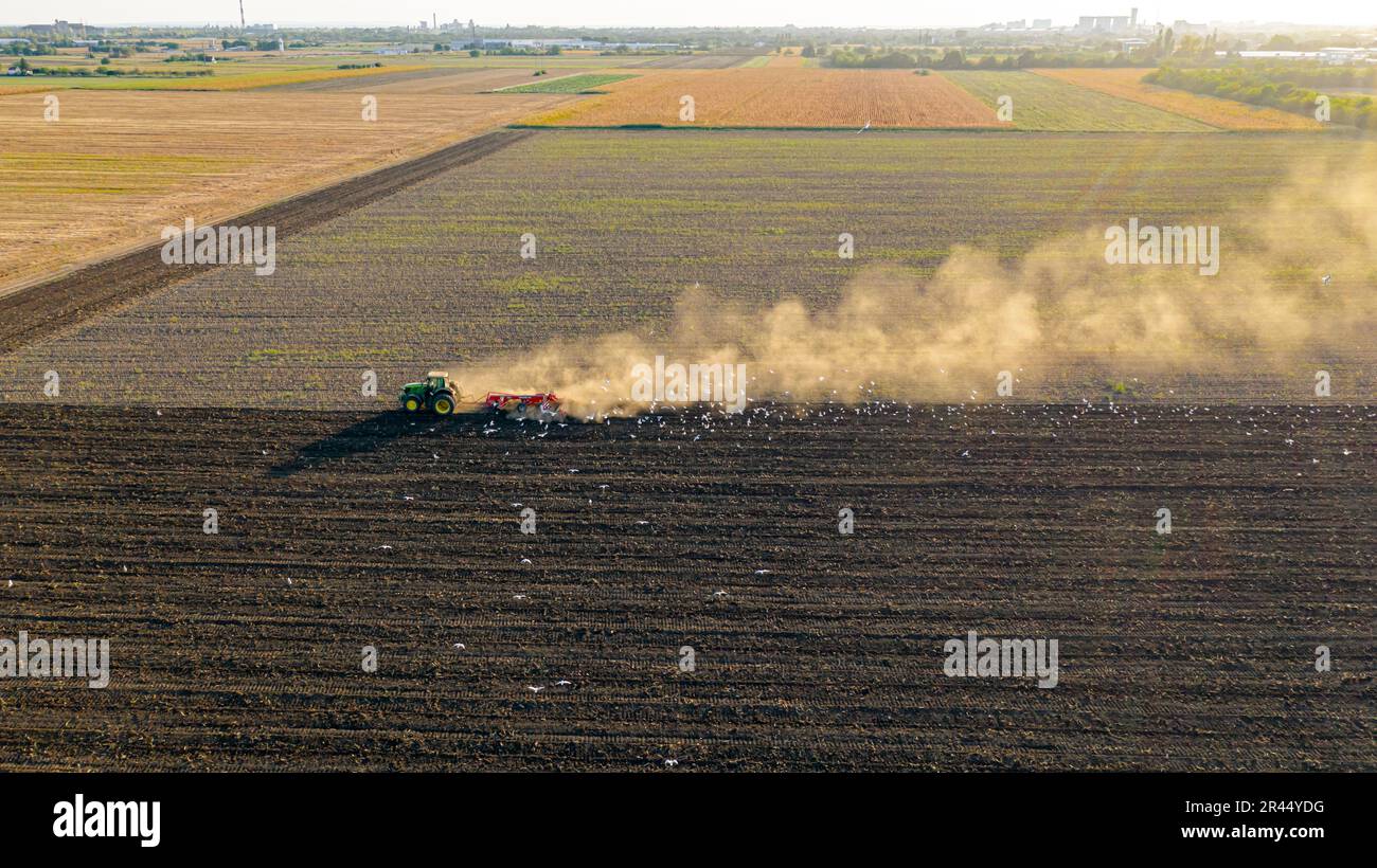 Above view with backlight, tractor pull disc harrow, harrowing farmland ...