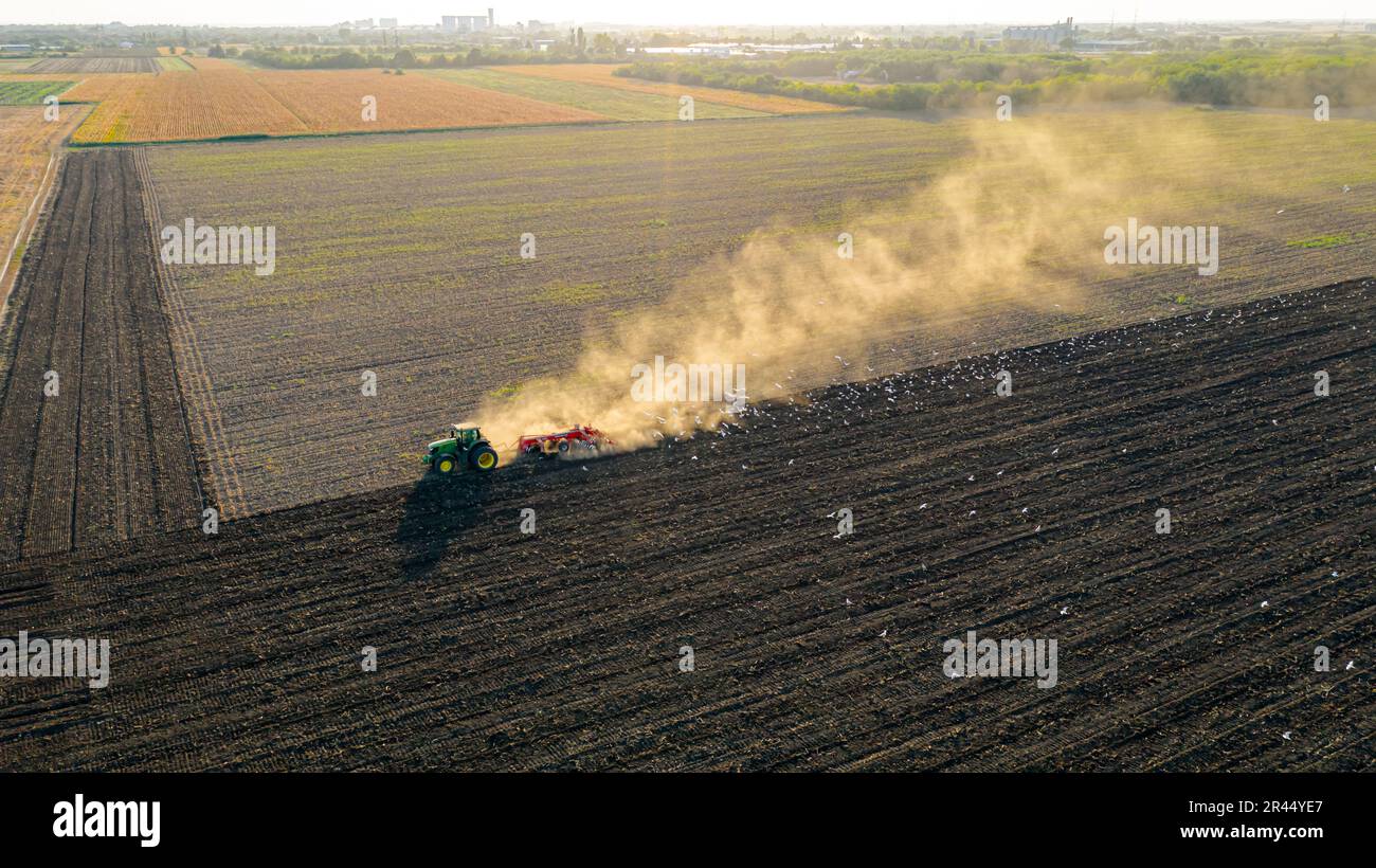 Above view with backlight, tractor pull disc harrow, harrowing farmland ...