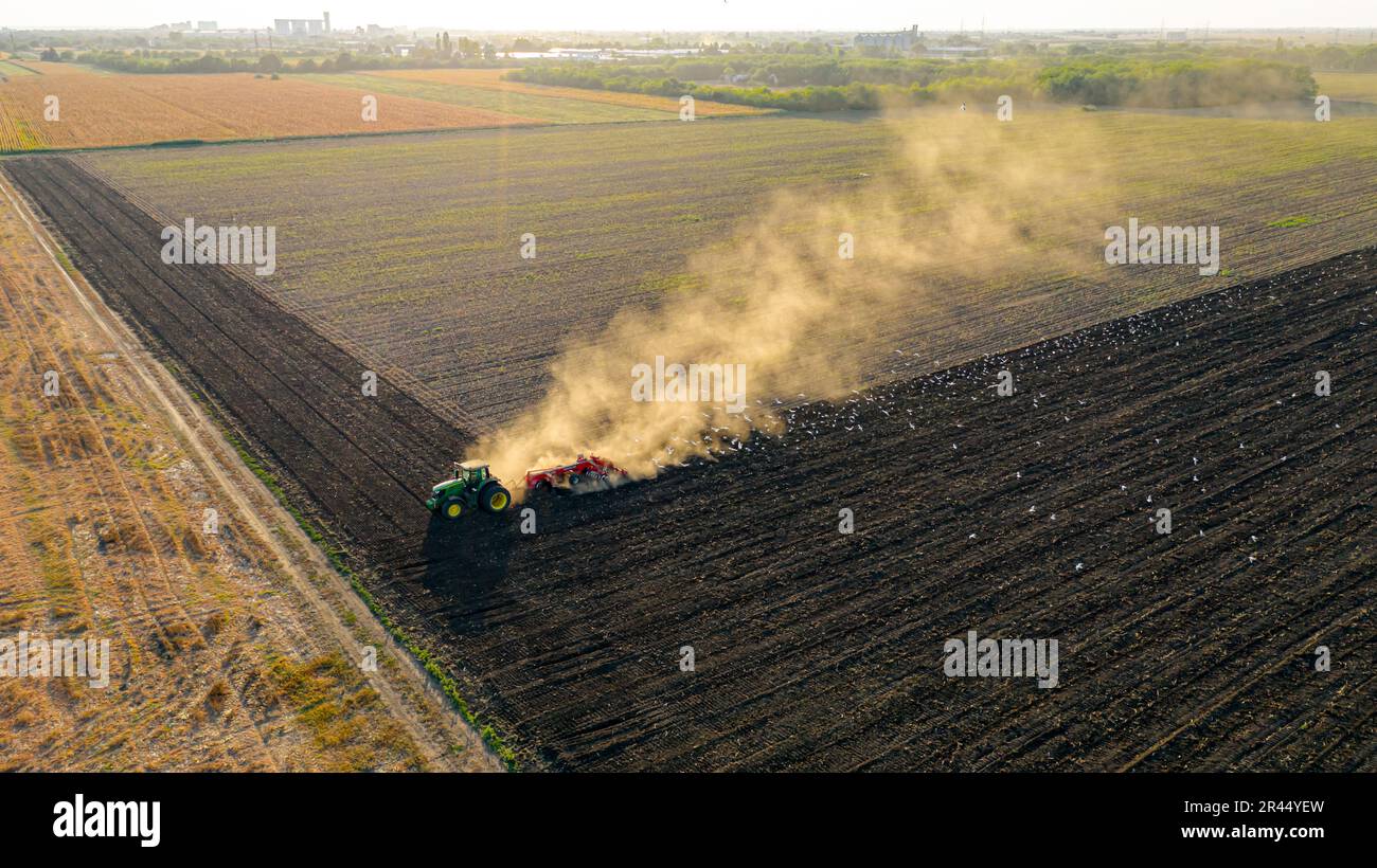 Above view with backlight, tractor pull disc harrow, harrowing farmland ...